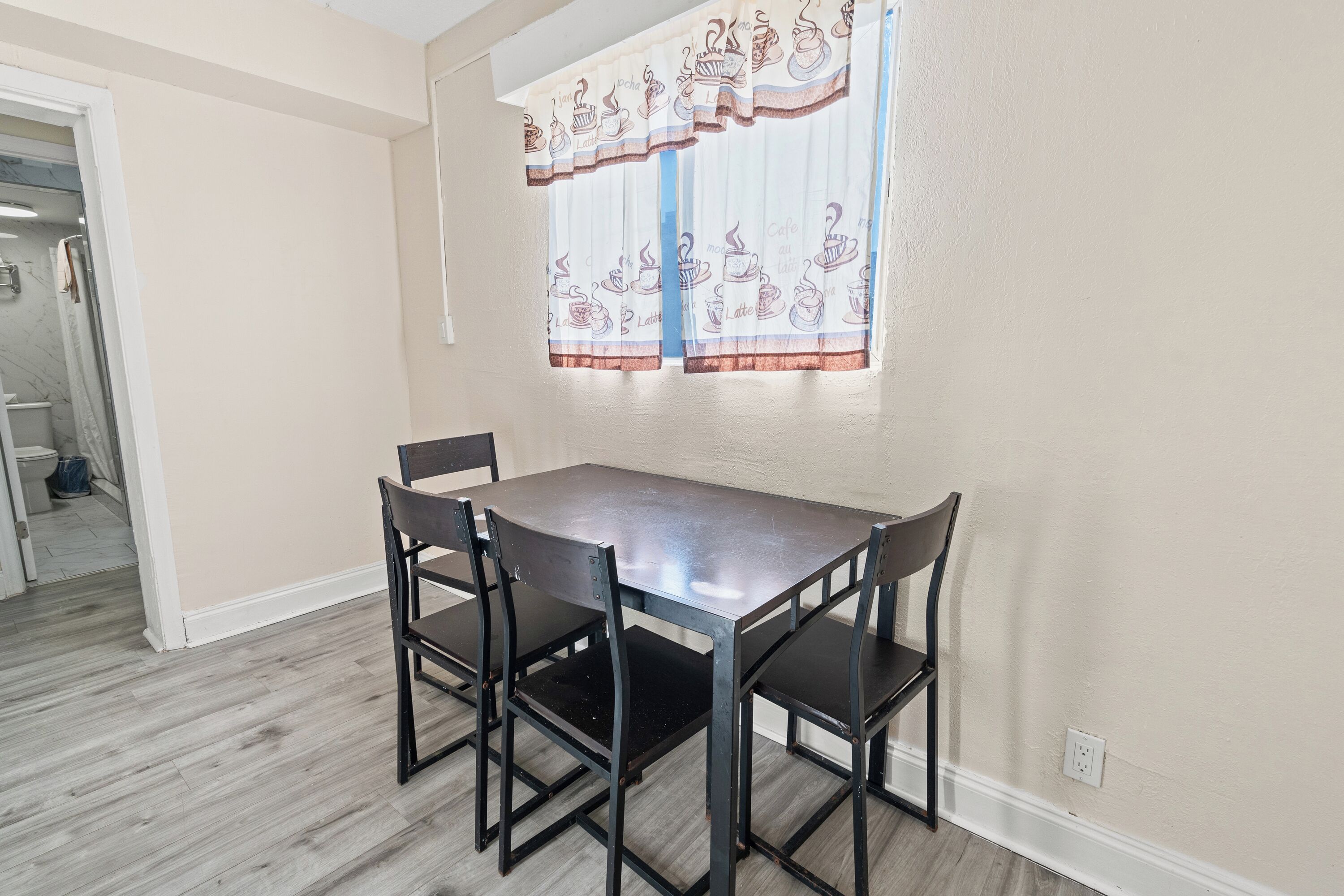Uma área de refeições com uma mesa retangular e quatro cadeiras.