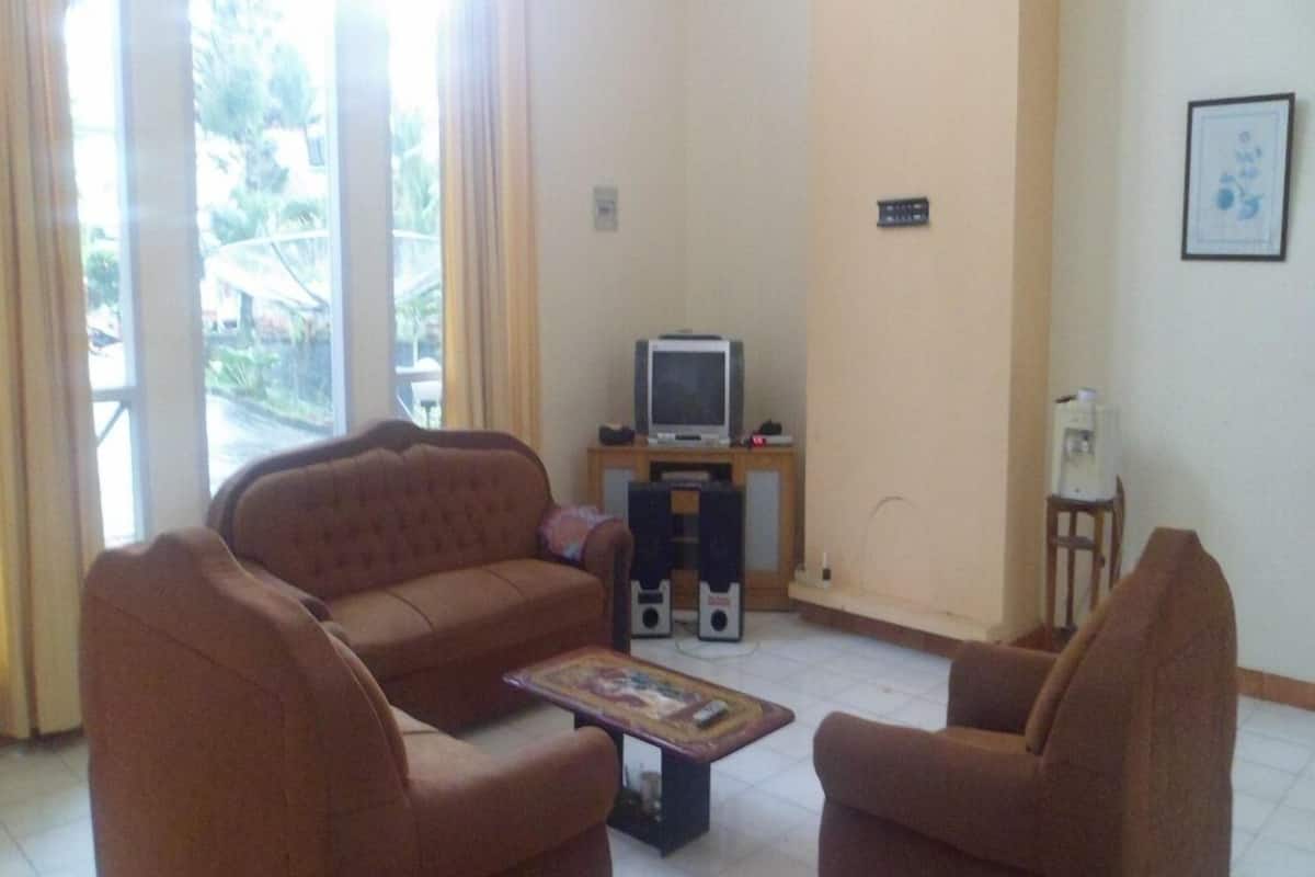 Uma sala de estar com sofá, duas poltronas, mesa de centro e televisão.