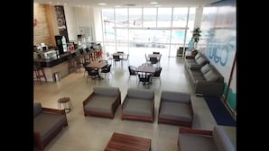 Um espaço amplo e interno com disposição de assentos, um balcão e uma grande janela com vista.