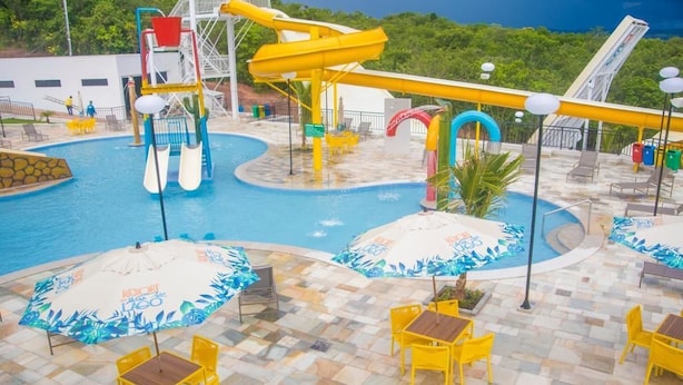 Área de piscina com toboáguas, espreguiçadeiras e guarda-sóis.