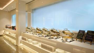 Uma área de buffet com diversas opções de comida e sinalização indicando pratos como omelete, ovo frito e dosa.