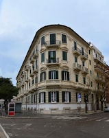 Um edifício de vários andares com fachada curva, varandas e um sinal de estacionamento.