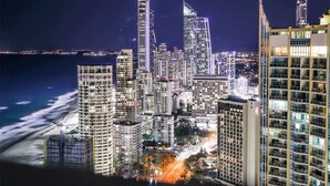 Paisagem urbana noturna com edifícios altos, uma orla marítima e vista para o oceano.