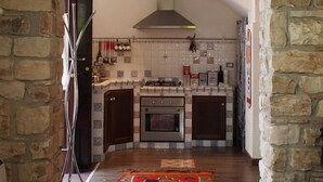 Cozinha com arco de pedra, revestimento de azulejos e fogão moderno.