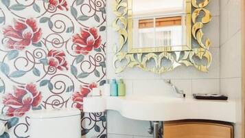 Casa de banho com sanita, lavatório e espelho decorativo.