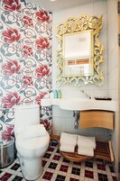 Casa de banho com sanita, lavatório e espelho decorativo.