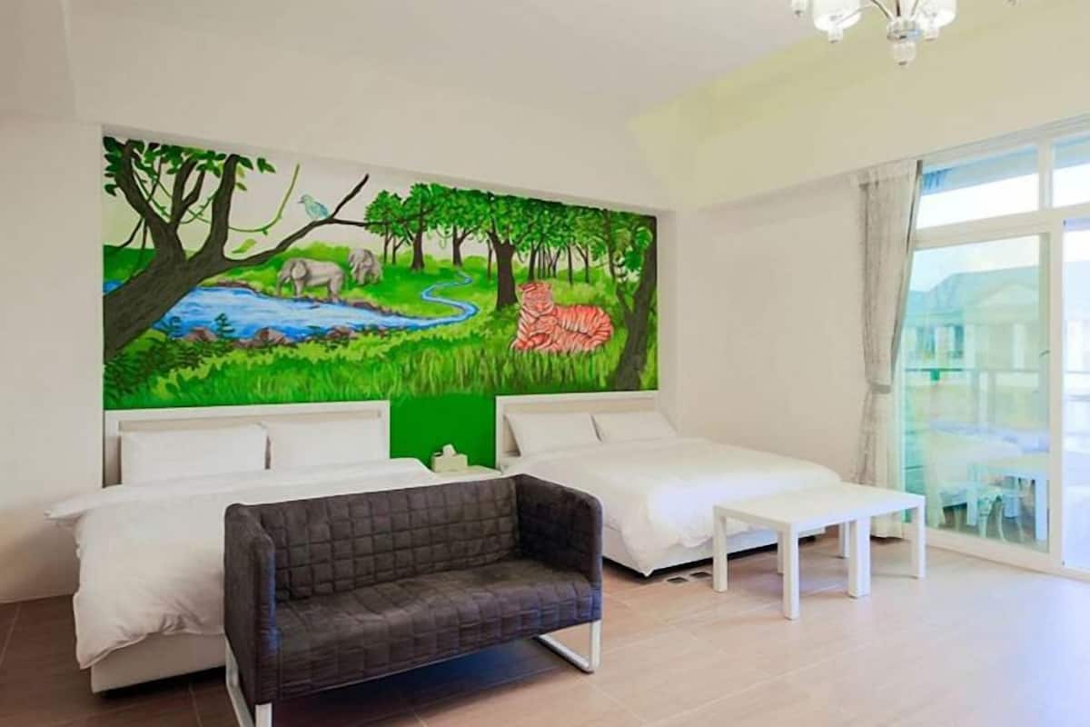 Uma sala de estar moderna com um quadro grande retratando uma cena florestal, um sofá, uma poltrona e vista para um horizonte urbano através de janelas amplas.