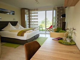 Quarto de hotel com cama, mesa de jantar, cadeira, planta e vista para o exterior.