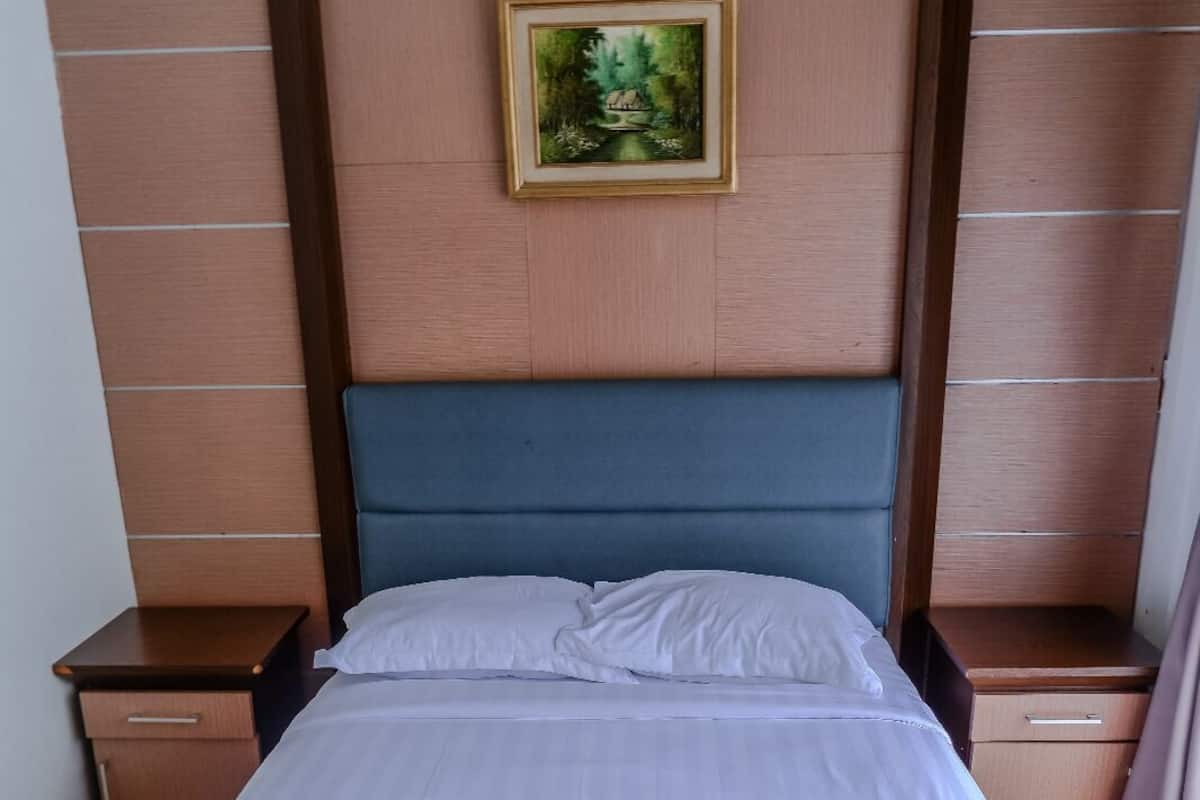 Cama bem arrumada com lençóis brancos, cabeceira de madeira e uma pequena moldura acima.