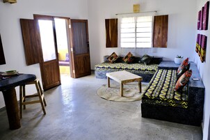 Quarto com sofá, mesa de madeira e janela com cortinas.