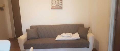 Sala de estar com sofá, mesa pequena e uma obra de arte na parede.
