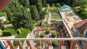 Um jardim modelo com estufa, caminhos de tijolo e diversas plantas.