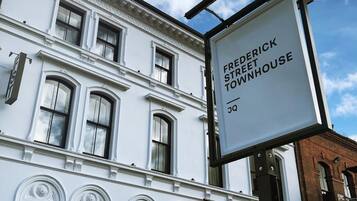 Uma casa urbana branca com uma placa que diz 'Frederick Street Townhouse'.