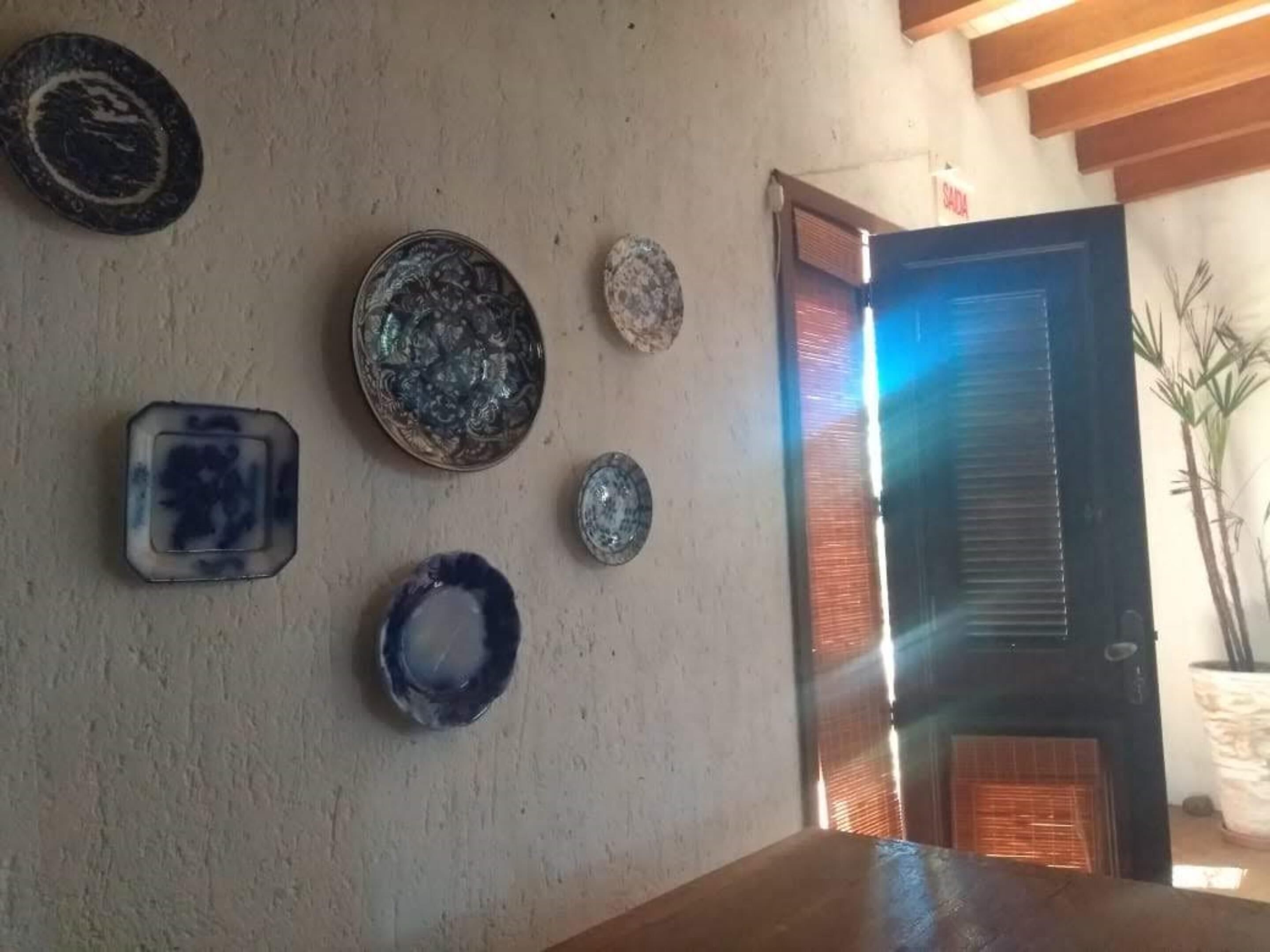 Paredes decoradas com diversos pratos e uma porta com grade de metal.