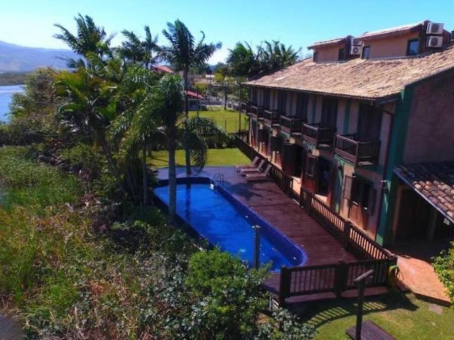 Um hotel com piscina, rodeado por vegetação exuberante e vista para um corpo de água.