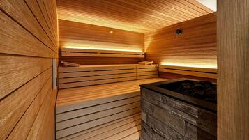 Uma sauna com ripas de madeira e um banco de pedra.