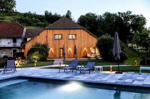 Uma casa de madeira com piscina, área de estar externa e um pátio bem iluminado.