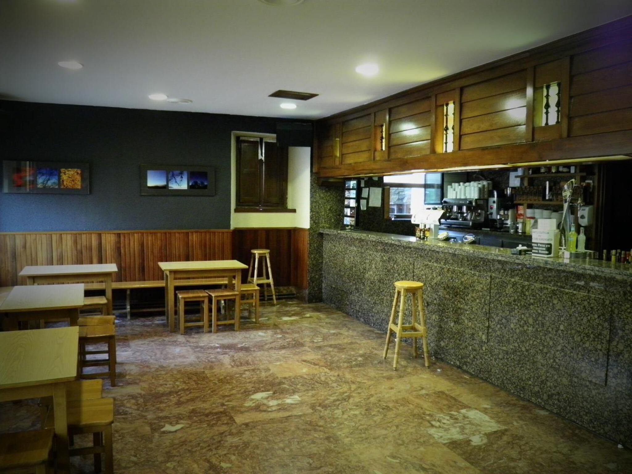 Restaurante com cabines de madeira, área de bar e piso de pedra.