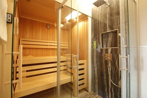Uma sala de sauna com bancos de madeira e um box de chuveiro envidraçado.