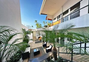 Um edifício moderno com um pátio que inclui área de estar ao ar livre e palmeiras.