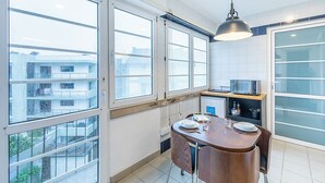 Cozinha com grandes janelas, mesa de jantar e micro-ondas.