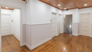 Um corredor com piso de madeira, paredes brancas e várias portas.