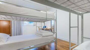 Quarto com beliche, escrivaninha e cadeira, janela e porta.