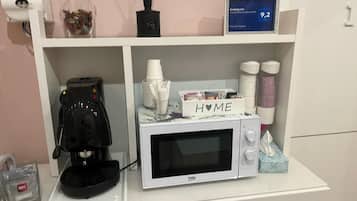 Uma cozinha compacta com cafeteira, micro-ondas e uma placa com a inscrição 'CASA'.