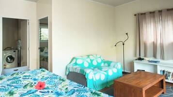 Quarto com uma cama, uma escrivaninha, uma cadeira, uma máquina de lavar e uma estante de livros.