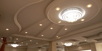 Teto com iluminação embutida e um lustre central.