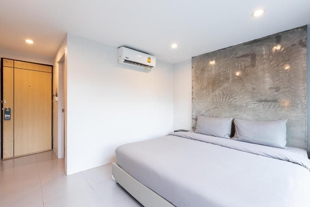 Quarto de hotel moderno com uma cama grande, ar condicionado e uma porta de madeira.