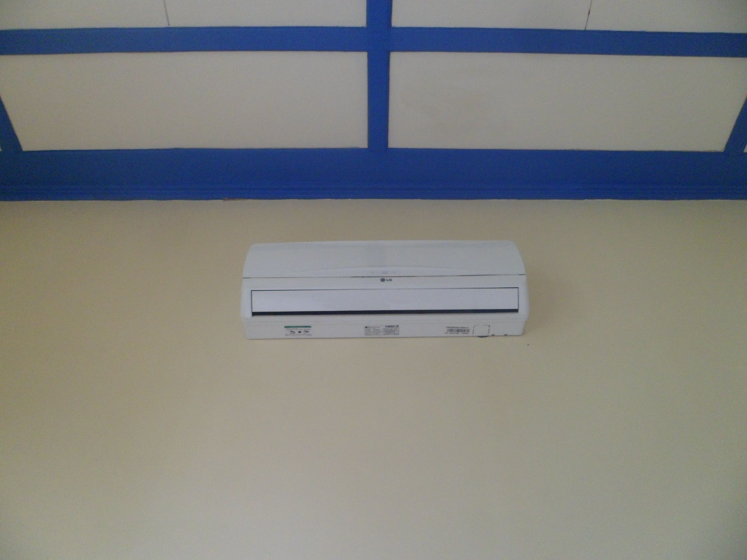 Ar condicionado branco da LG fixado na parede, com um padrão azul e branco.