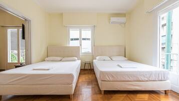 Quarto com duas camas, janela e ar condicionado.