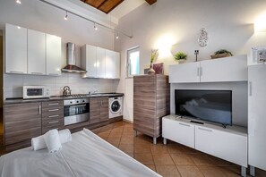 Cozinha moderna com armários brancos, micro-ondas, fogão e máquina de lavar.