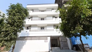 Um edifício de vários andares com telhado plano, paredes externas brancas e várias varandas.