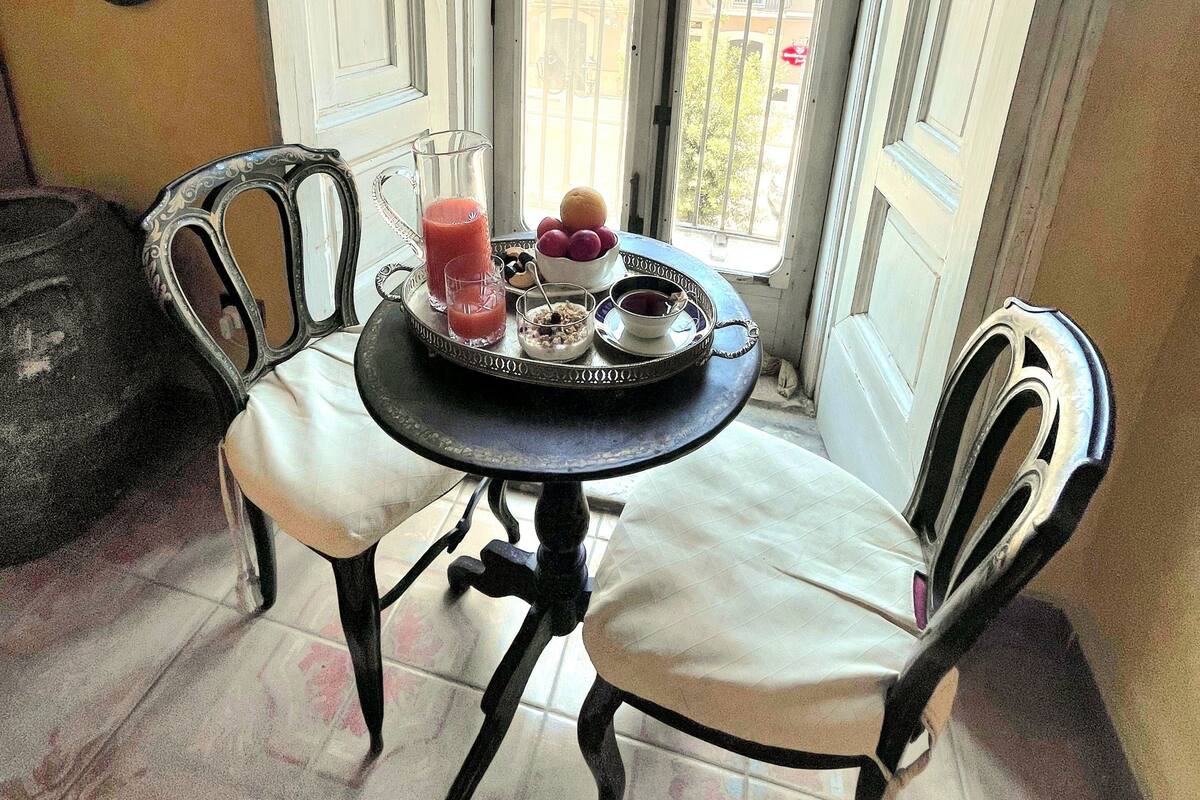 Varanda com mesa posta para o café da manhã, incluindo bebida, fruta e cereal.
