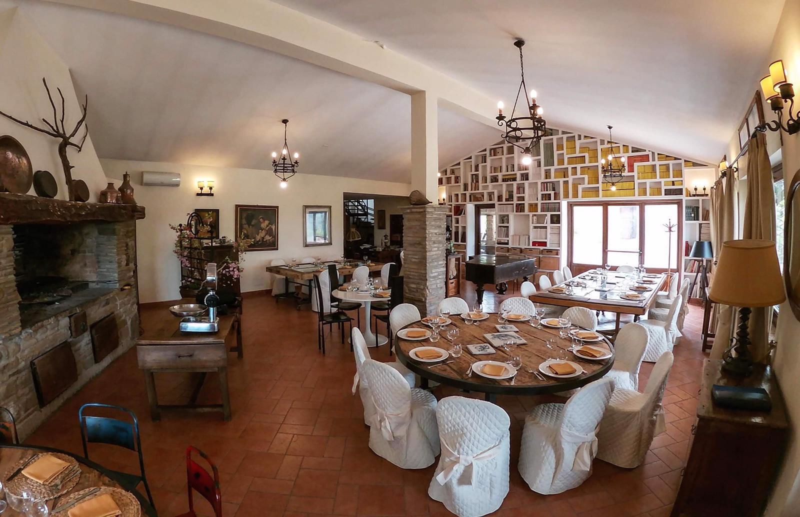 Uma sala de jantar ampla com pé direito alto, lareira e piano.