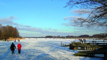 Um lago congelado com pessoas patinando e caminhando sobre o gelo.