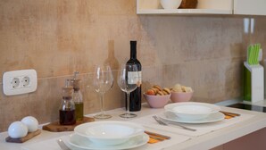 Uma bancada de cozinha com uma garrafa de vinho, copos, pratos e uma tigela de biscoitos.