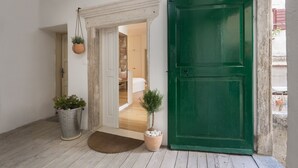 Um corredor com uma porta verde, um vaso de planta e piso de madeira.