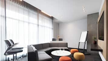 Uma sala de conferências moderna com um sofá curvo, mesa de centro redonda e um quadro branco.