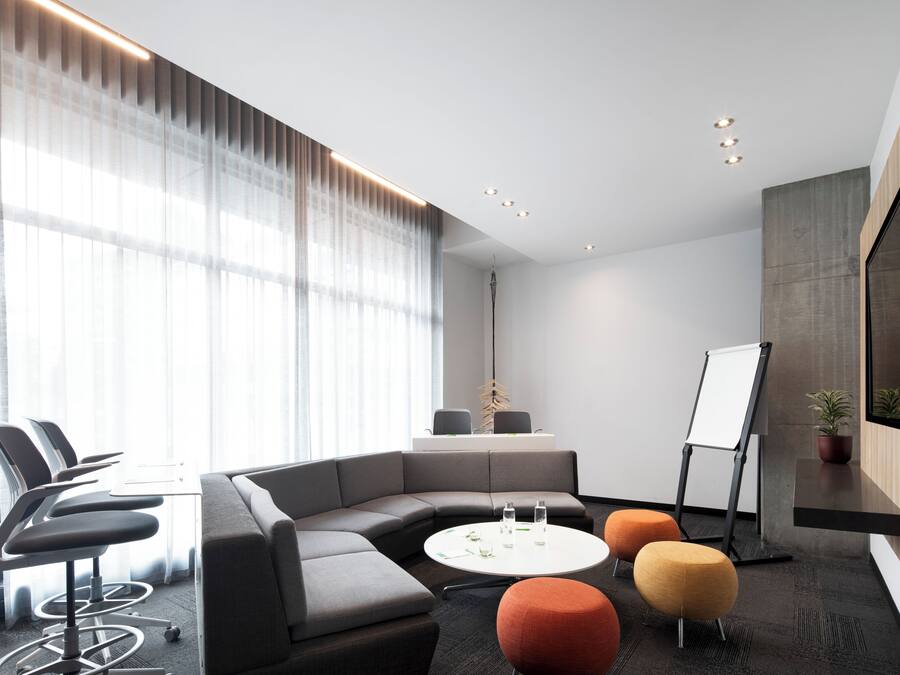 Uma sala de conferências moderna com um sofá curvo, mesa de centro redonda e um quadro branco.