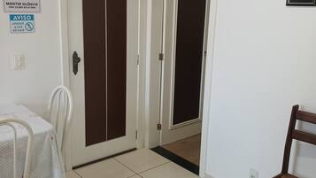 Quarto com uma mesa de jantar, cadeiras, um armário e uma porta com um aviso.