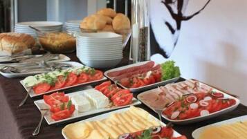 Buffet com diversos alimentos, incluindo saladas, carnes e queijos.