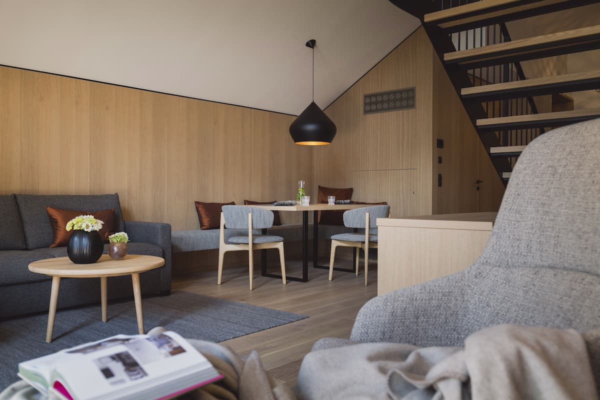 Uma sala de estar moderna com um sofá, uma mesa de centro e uma área de jantar com cadeiras.