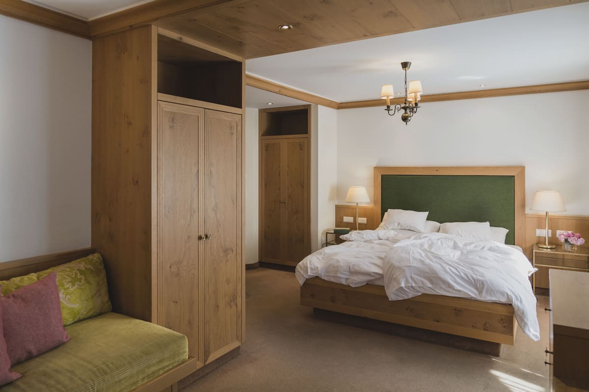 Quarto com cama de madeira, sofá verde e guarda-roupa.