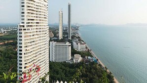Hotel alto com fachada curva, localizado perto de uma orla marítima, com vista para o mar e outros edifícios.