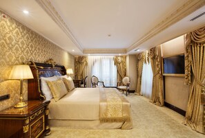 Um quarto de hotel luxuoso com uma cama grande, cortinas ornamentadas e uma televisão.