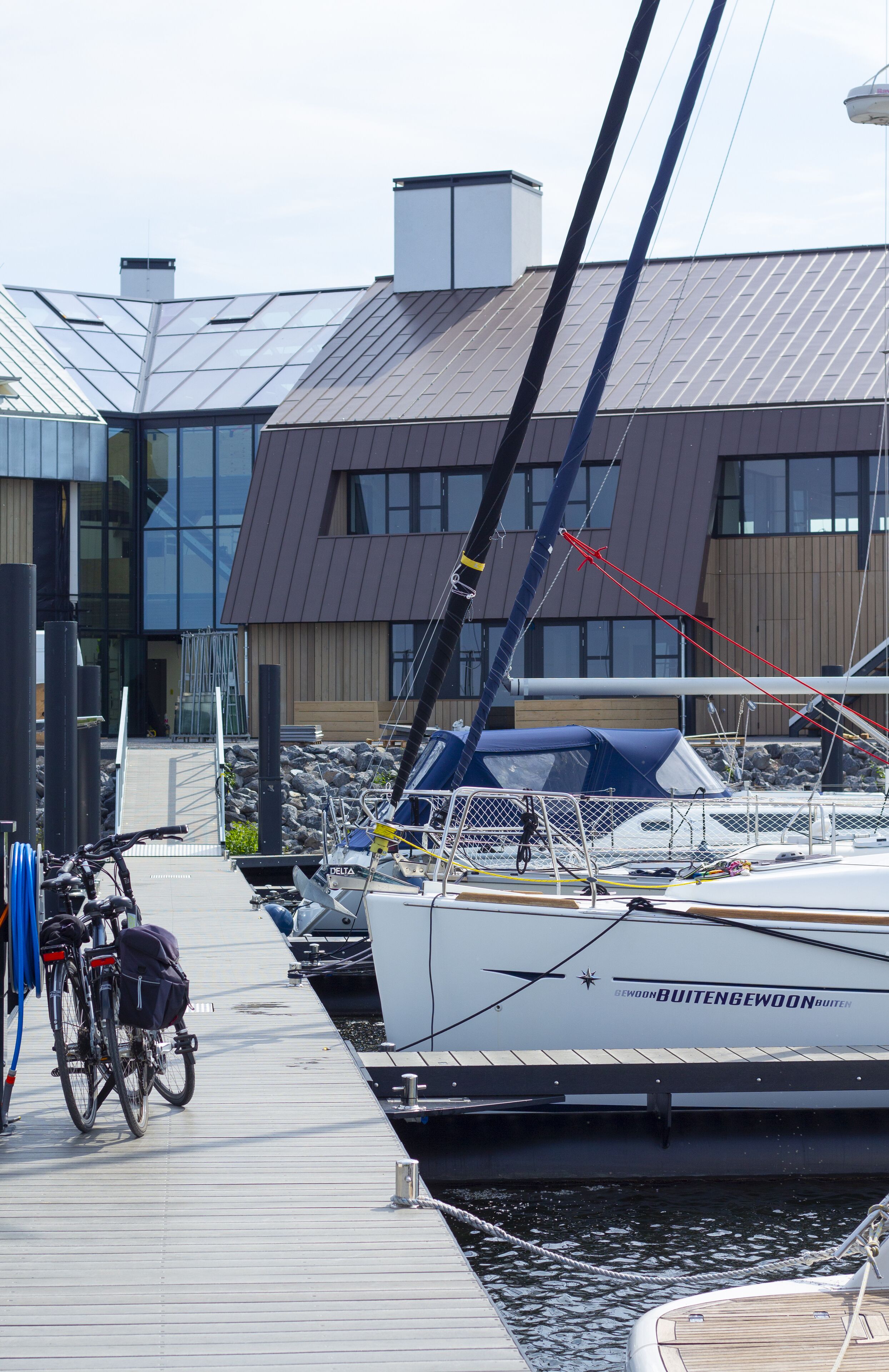 Uma marina com barcos atracados, uma bicicleta e um edifício moderno com grandes janelas.