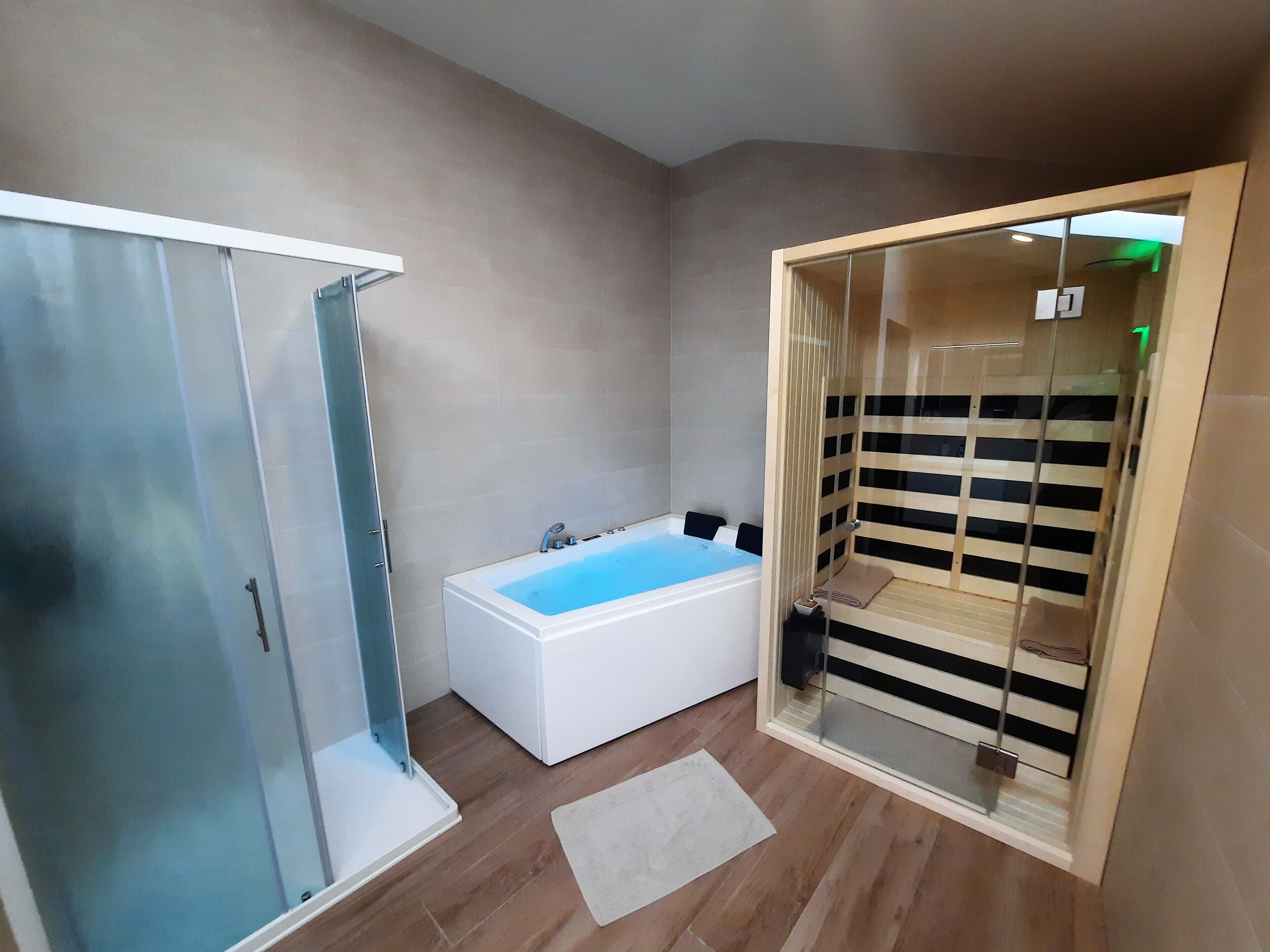 Uma casa de banho moderna com banheira, cabine de duche em vidro e um banco de madeira.